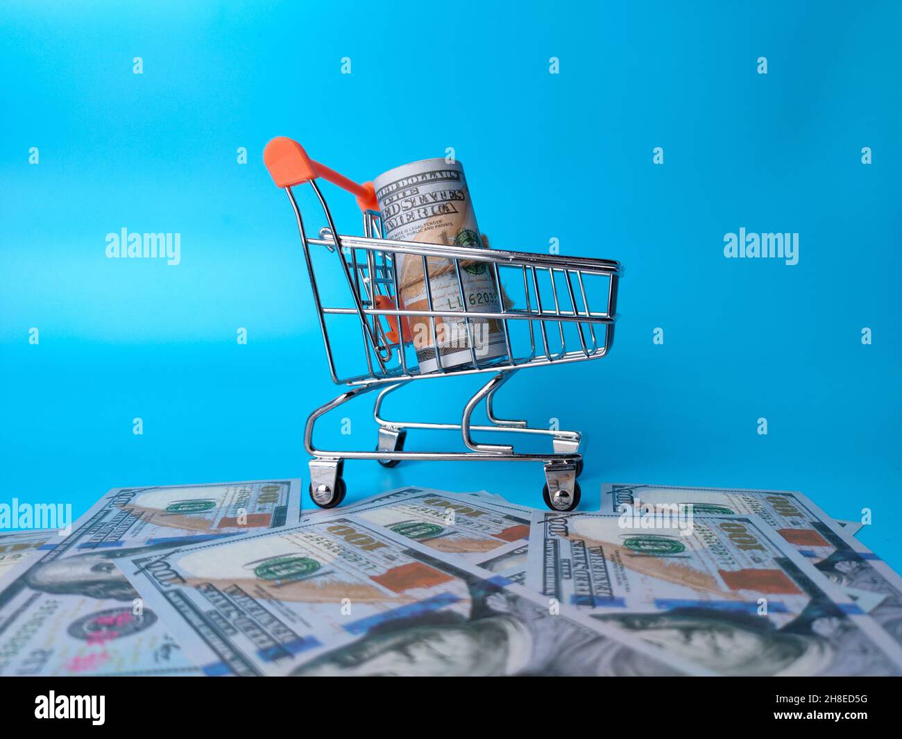 A fake dollar roll in a shopping trolley isolated on a blue background ...