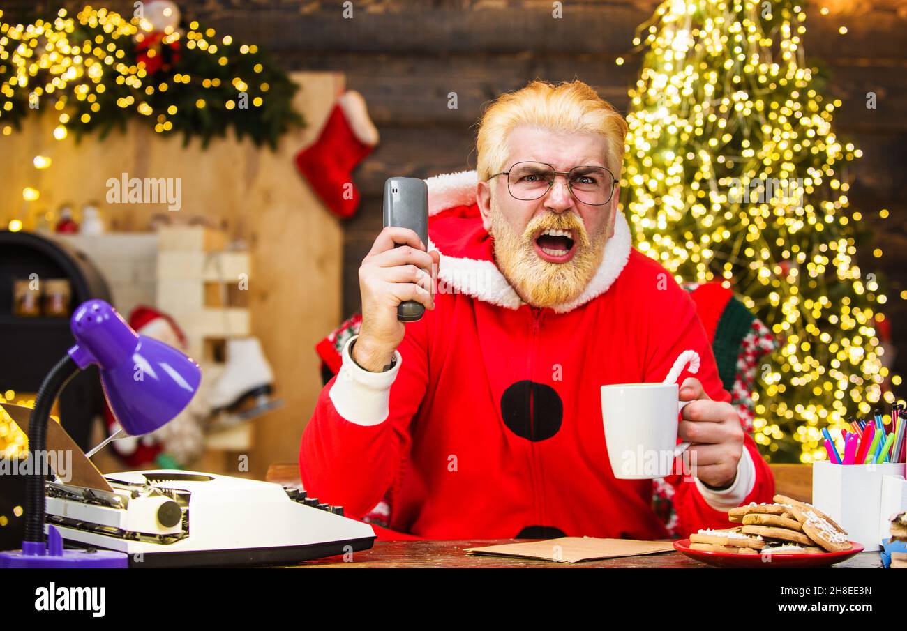 Angry Santa Claus sitting in armchair watching Christmas movie and ...