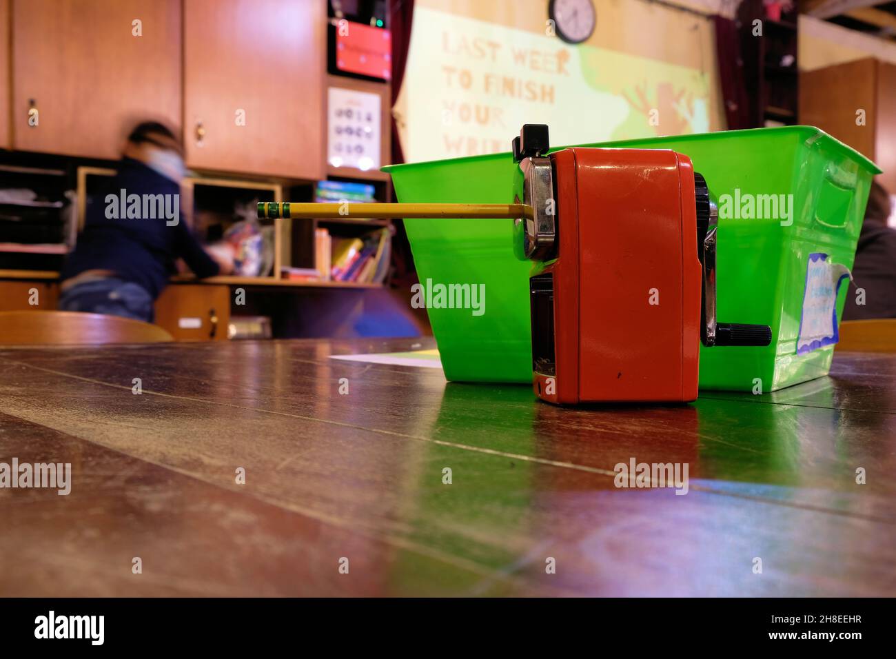 A pencil sharpener with a pencil inserted for sharpening on a wooden ...