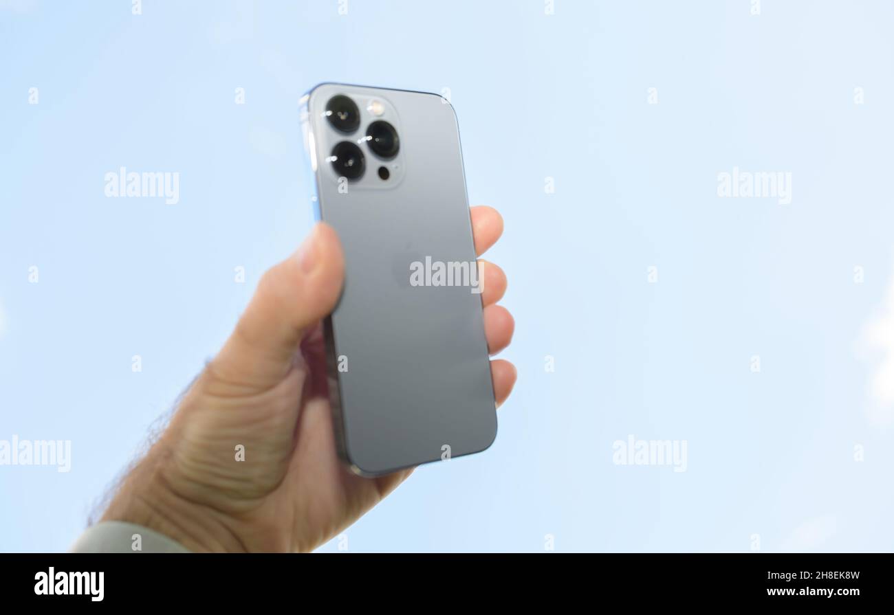 Male hand holding latest Apple Computers iPhone 13 pro with all three ...