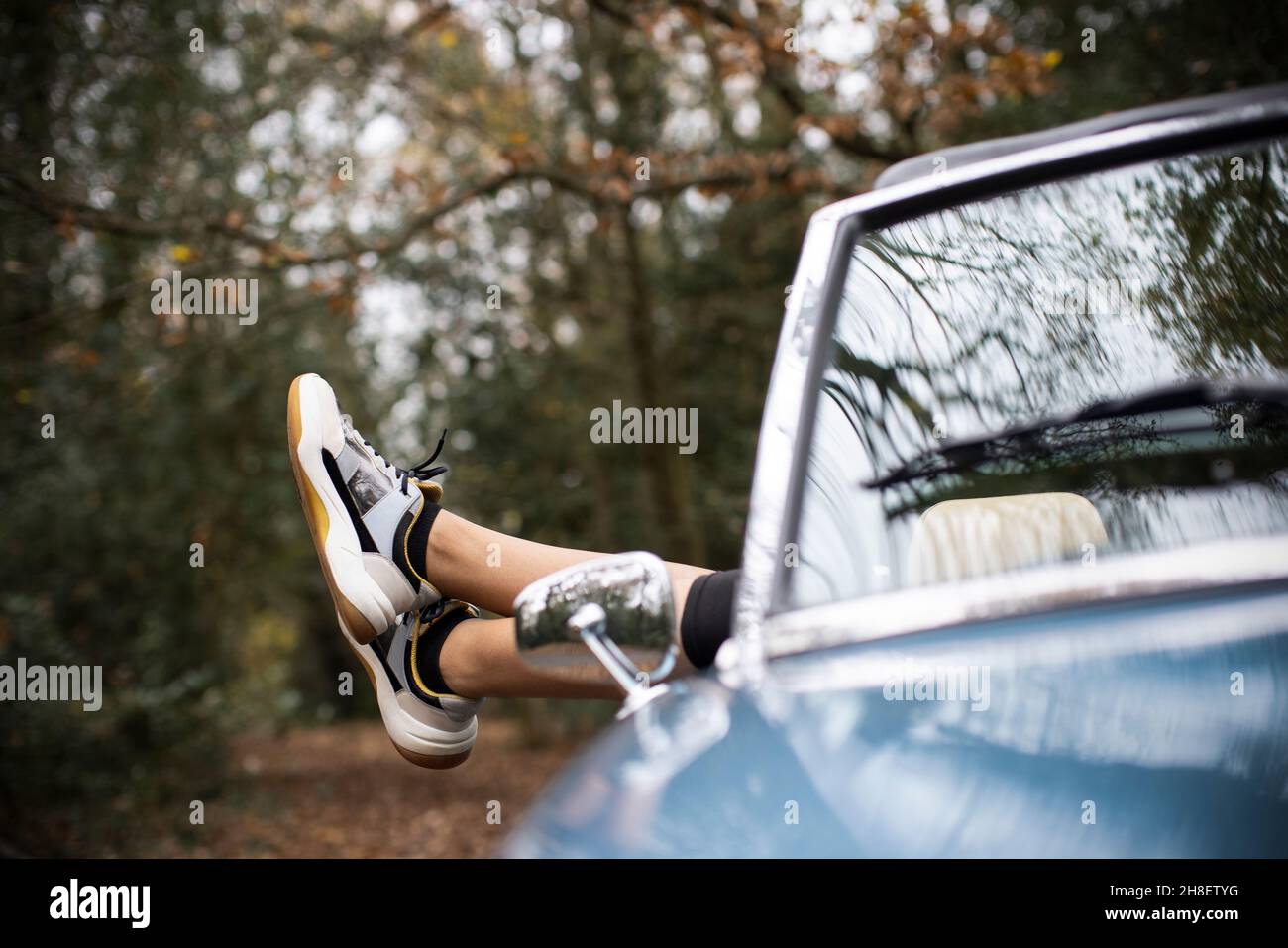 Carefree young woman relaxing in convertible with feet out window Stock ...