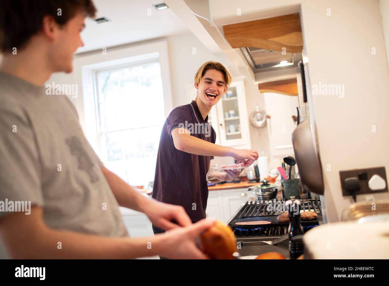 Happy teenage brothers cooking in kitchen Stock Photo - Alamy