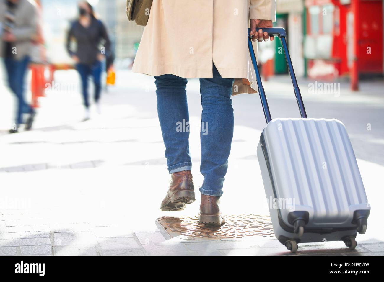 Male tourist pulling suitcase on city sidewalk Stock Photo - Alamy