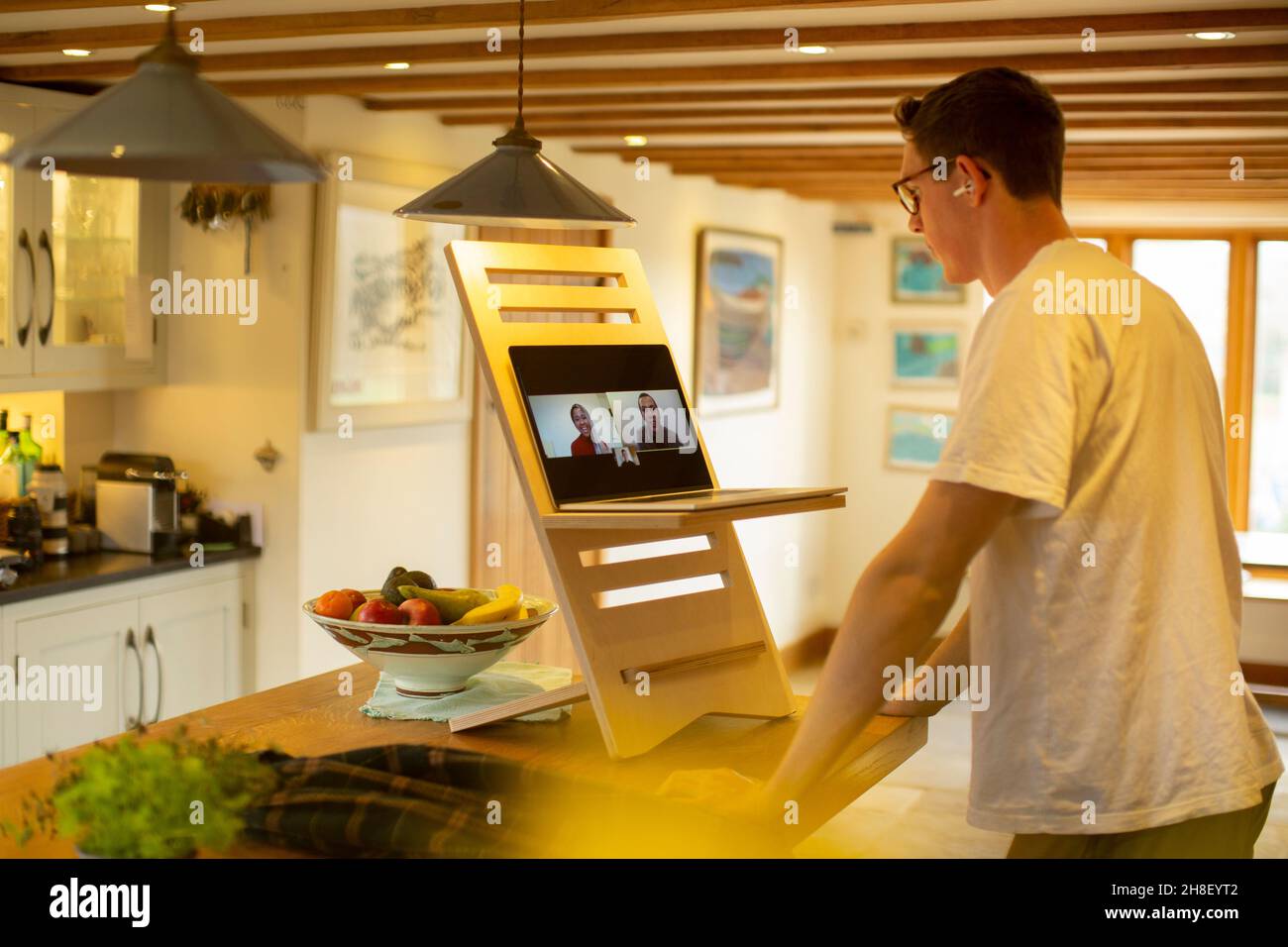 Man video conferencing at laptop stand desk in kitchen Stock Photo - Alamy