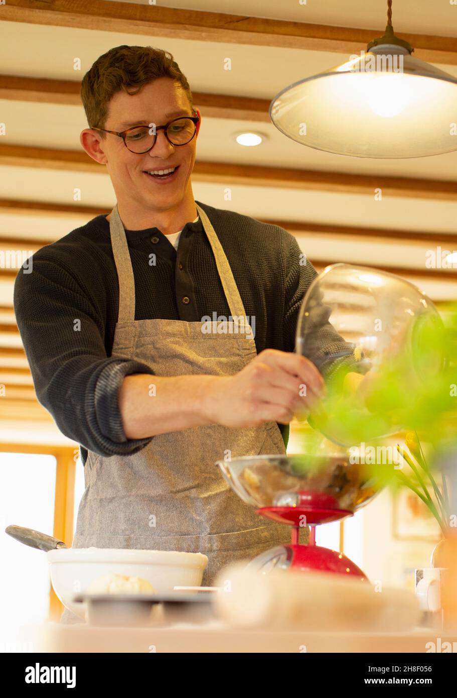 Smiling man baking using scale in kitchen Stock Photo - Alamy