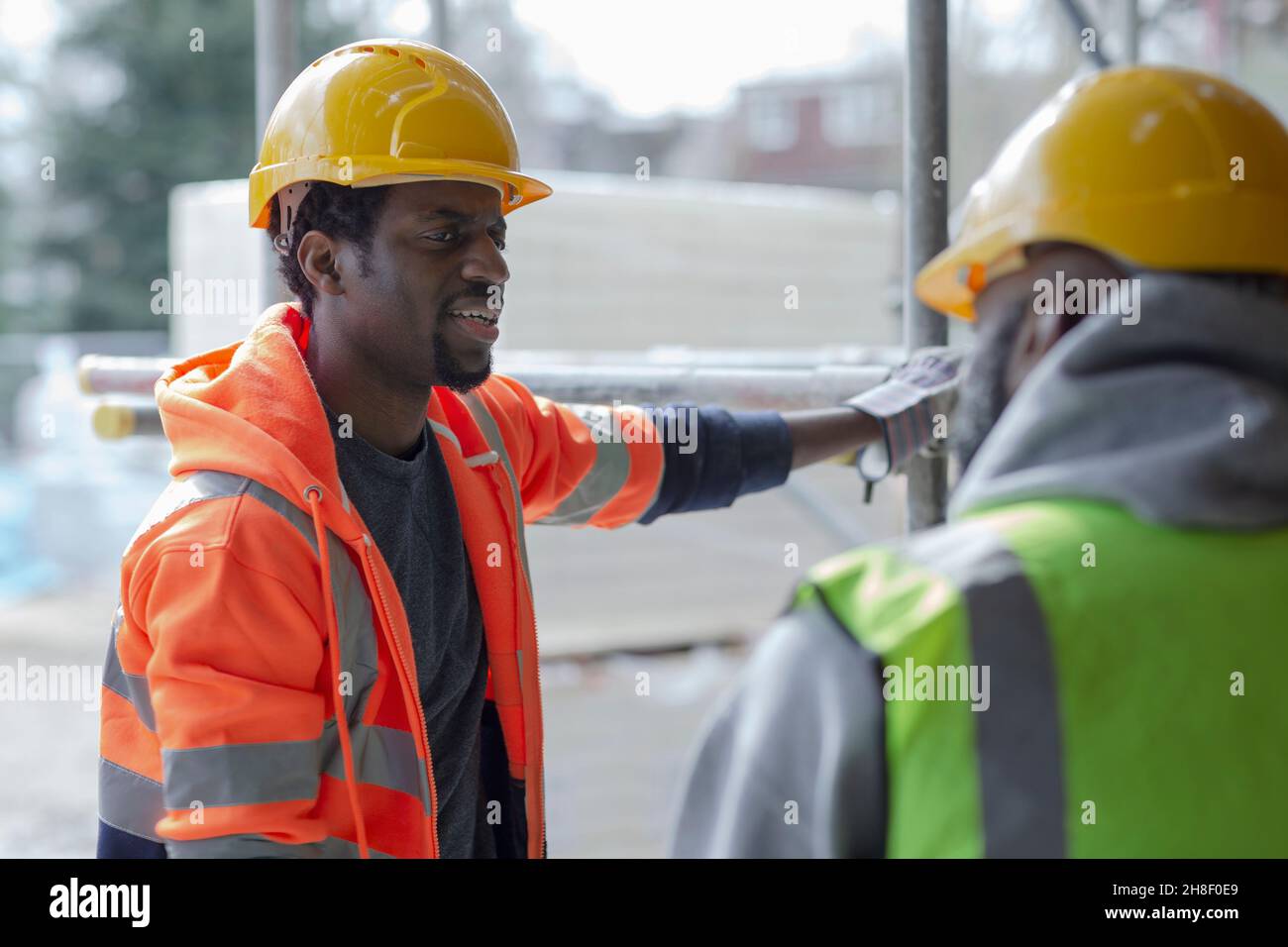 Male construction workers talking at construction site Stock Photo - Alamy