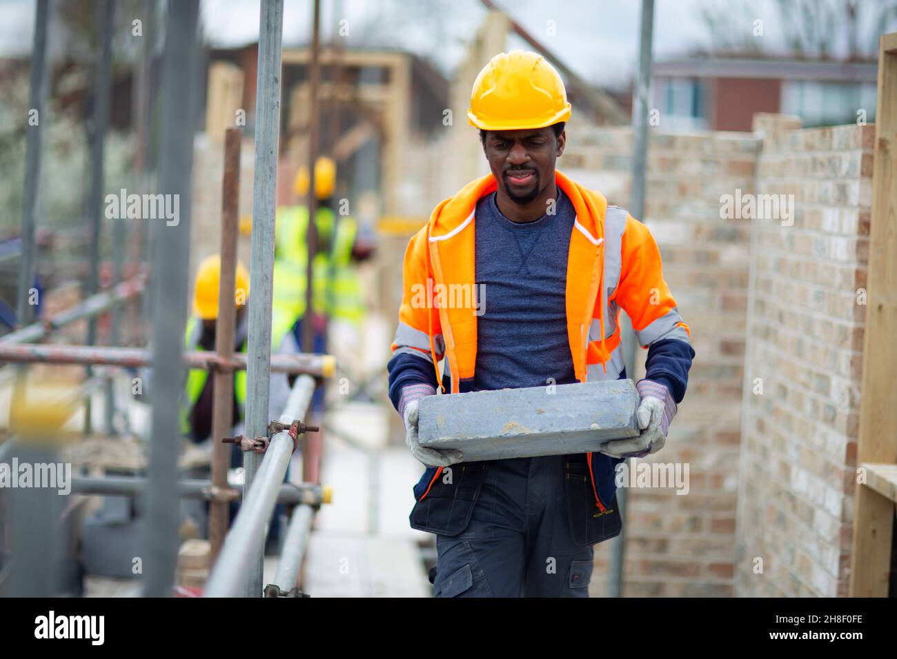 Male construction worker carrying brick at construction site Stock ...
