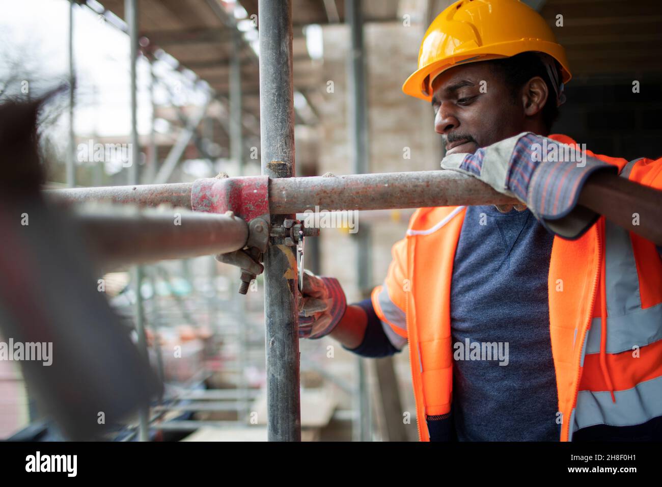 Male construction worker assembling scaffolding at construction site ...