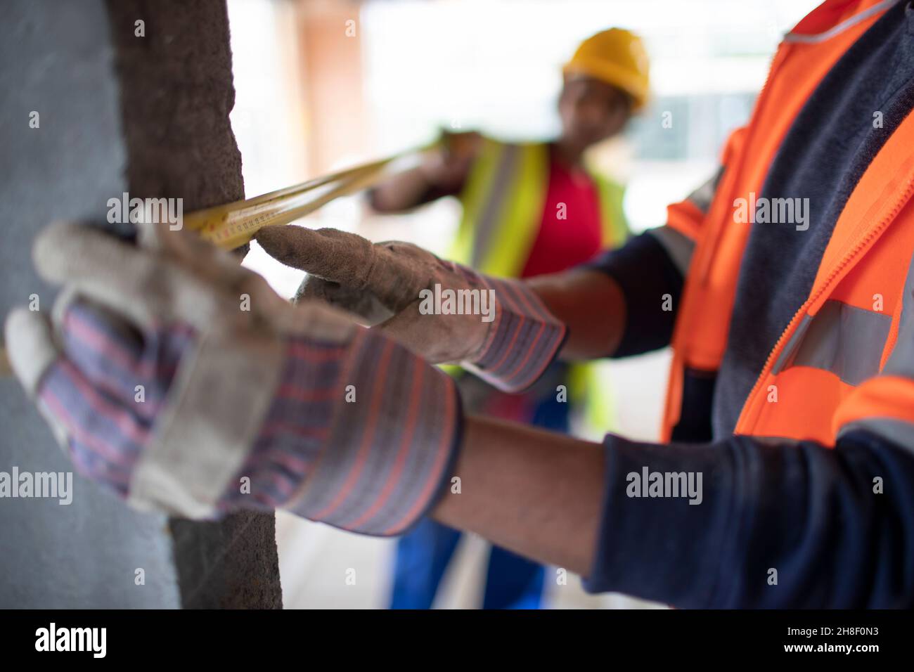 Close up construction workers using tape measure Stock Photo - Alamy