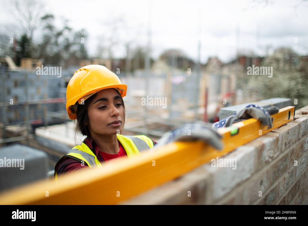 Female construction worker using level tool on brick wall Stock Photo ...