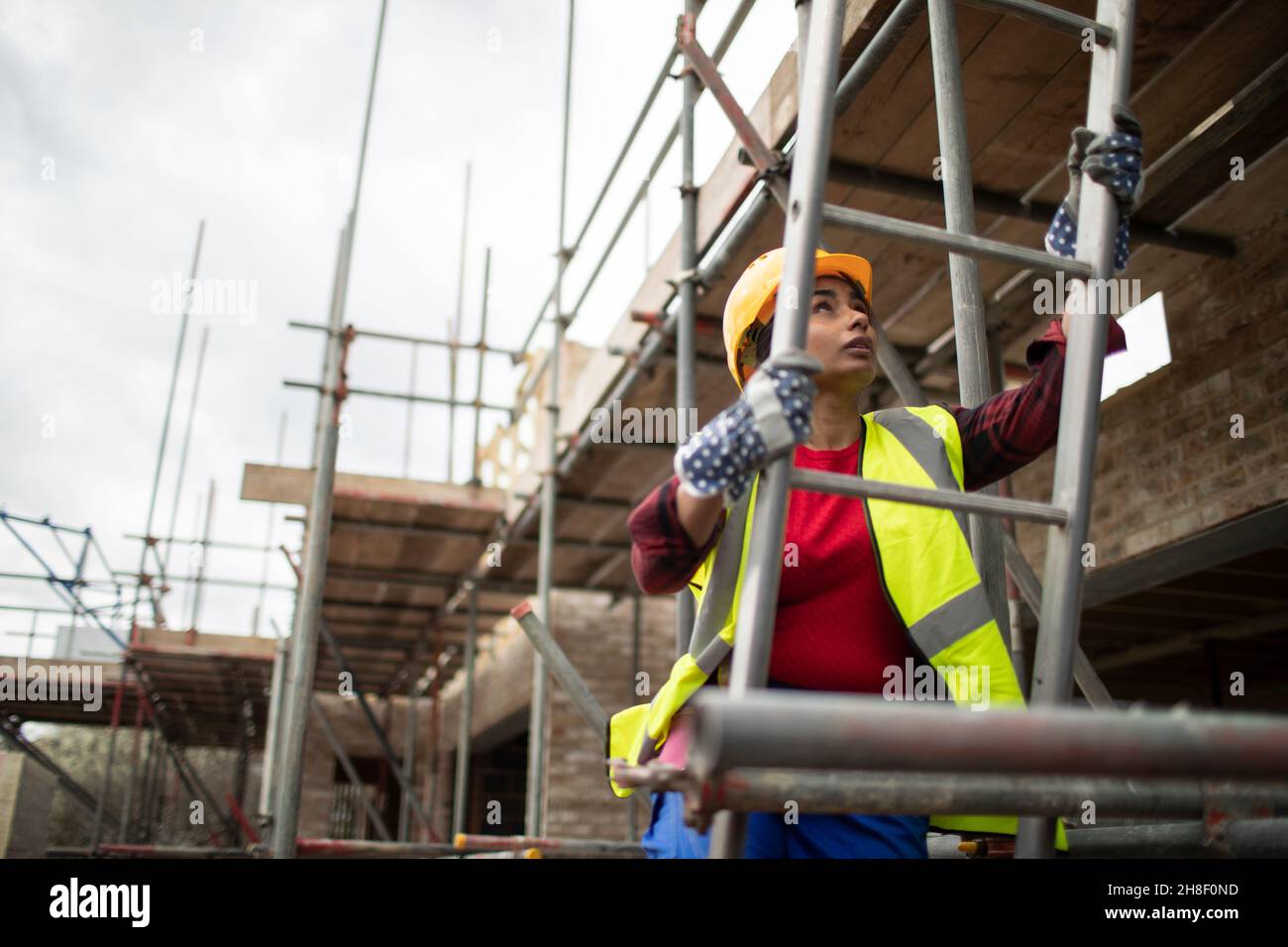 Female construction worker climbing ladder at construction site Stock ...