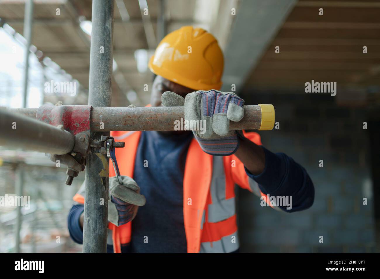Male construction worker assembling scaffolding at construction site ...