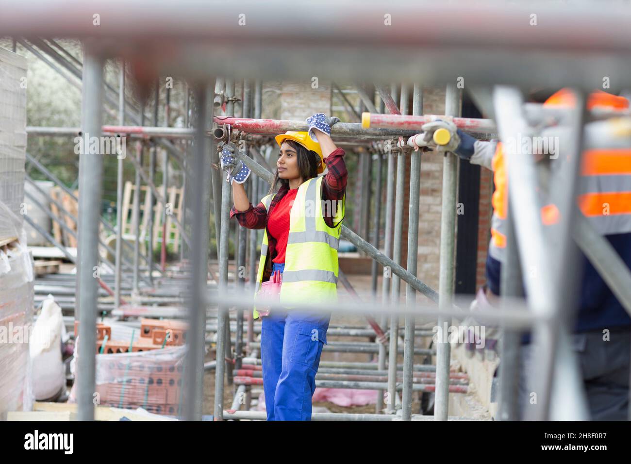 Female construction worker assembling scaffolding at construction site ...