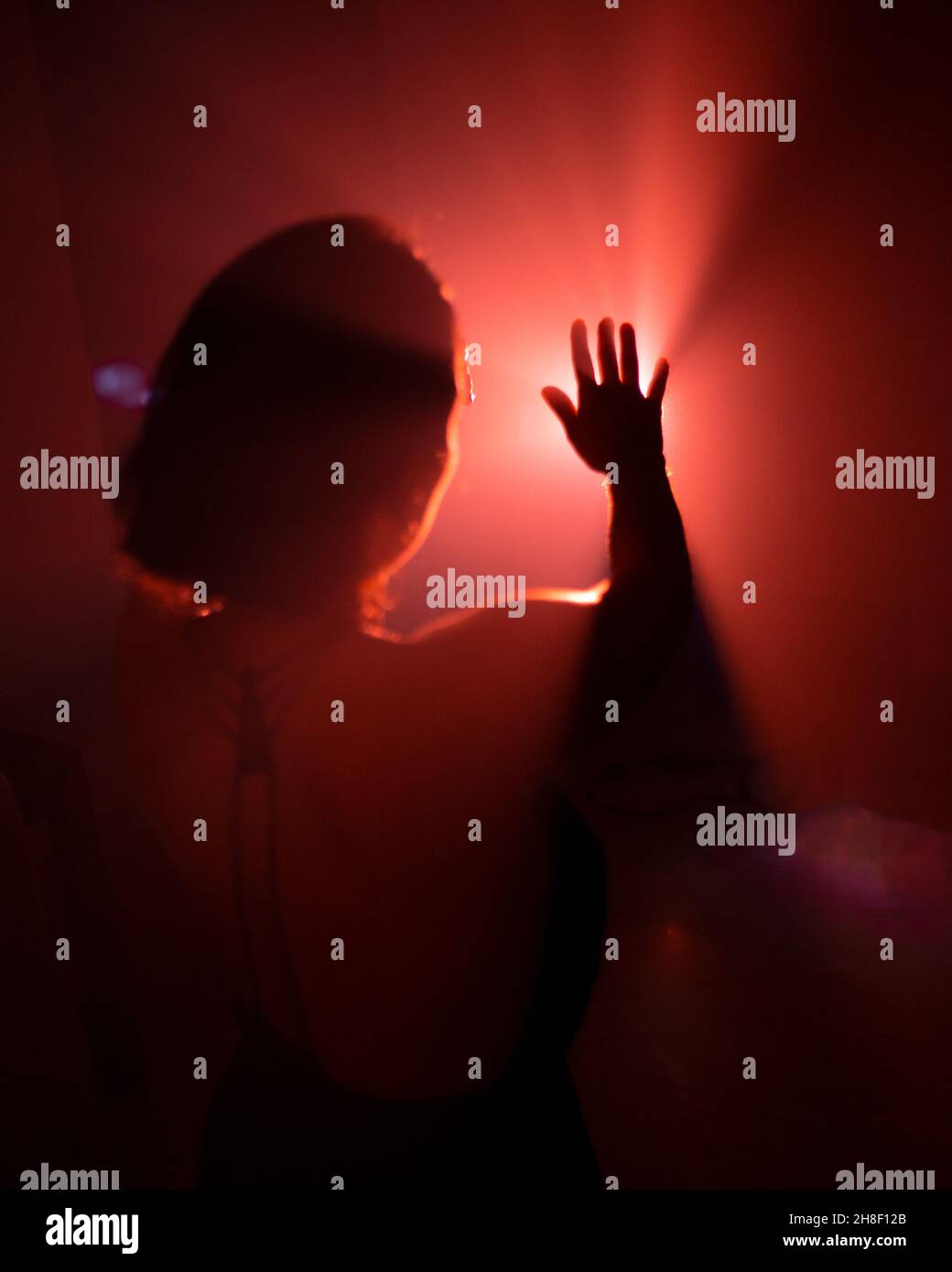 Back view of a woman covering a bright red laser projector with her ...