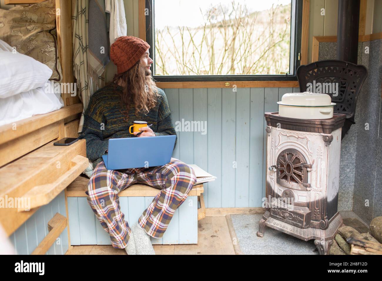 Thoughtful young man using laptop in tiny cabin rental Stock Photo - Alamy