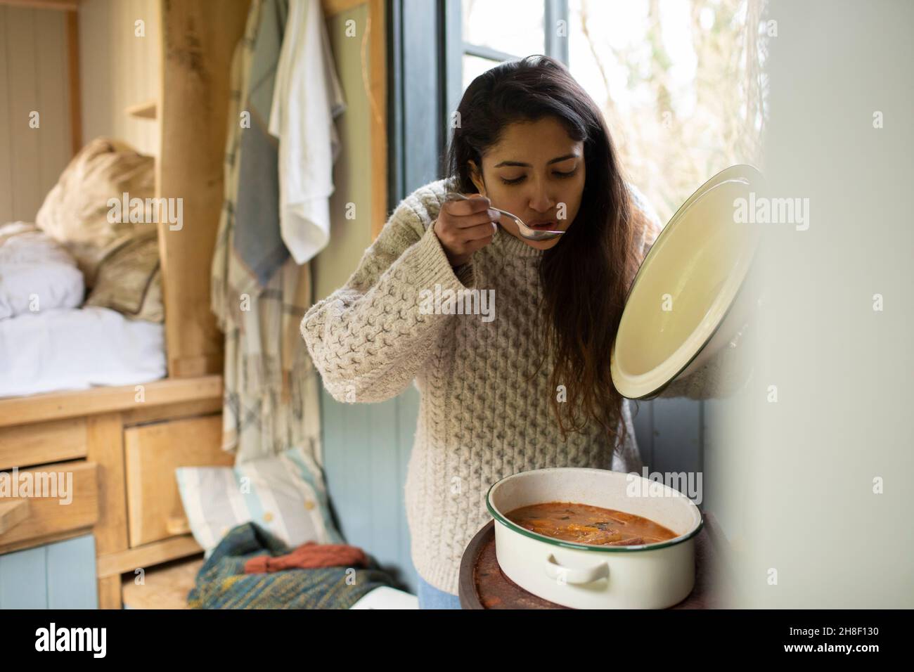 Young woman cooking stew in tiny cabin Stock Photo - Alamy