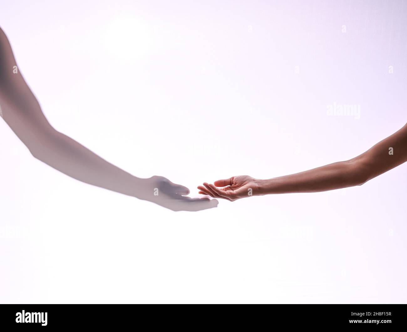 Female hand and a shadow of a male hand reaching each other isolated on ...