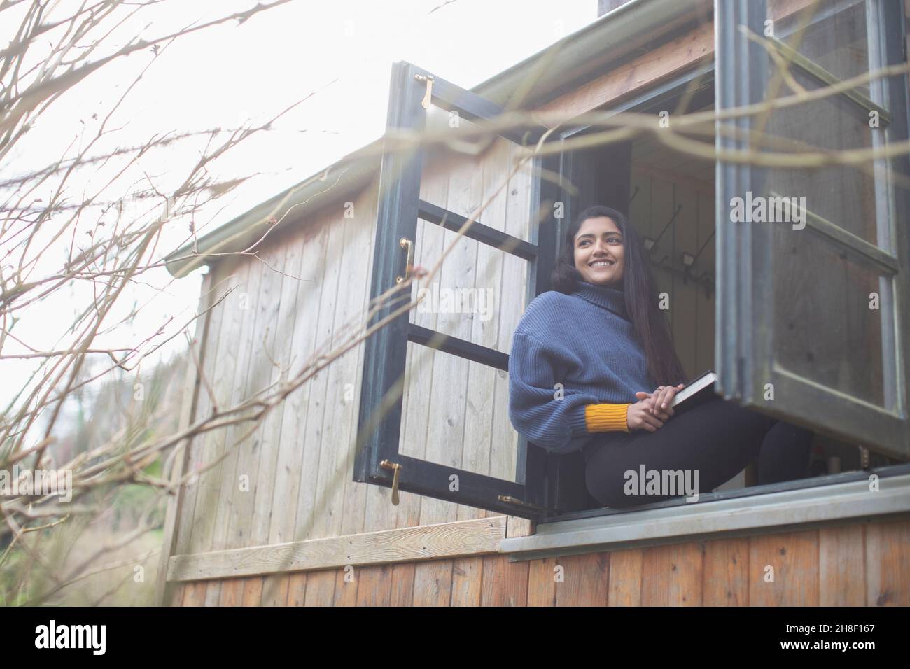 Happy young woman in tiny cabin rental window Stock Photo - Alamy
