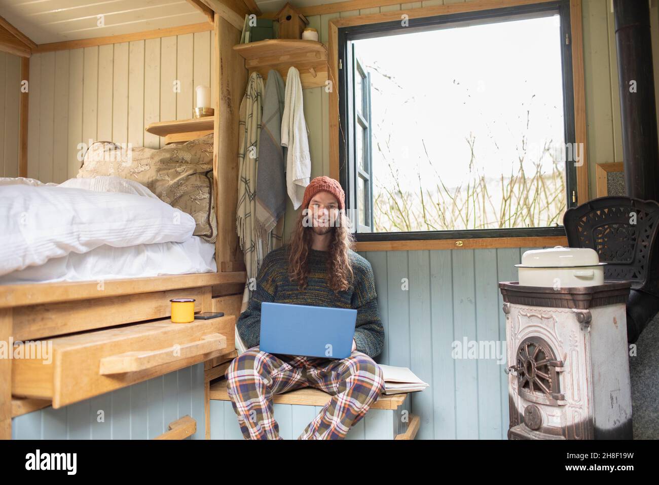 Portrait smiling young man using laptop in tiny cabin rental Stock ...