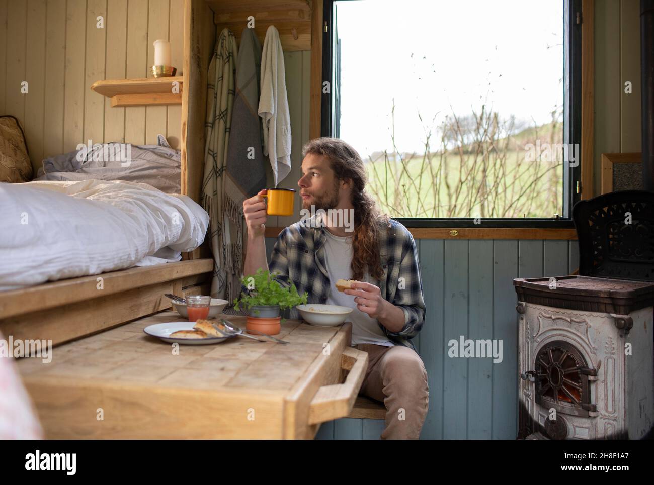 Young man eating and drinking in tiny cabin rental Stock Photo - Alamy