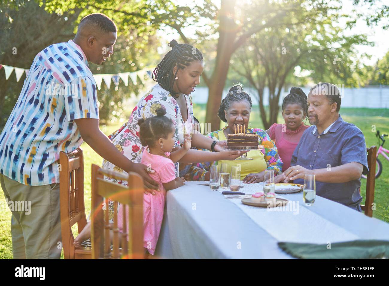Multigenerational family celebrating birthday at summer patio table ...