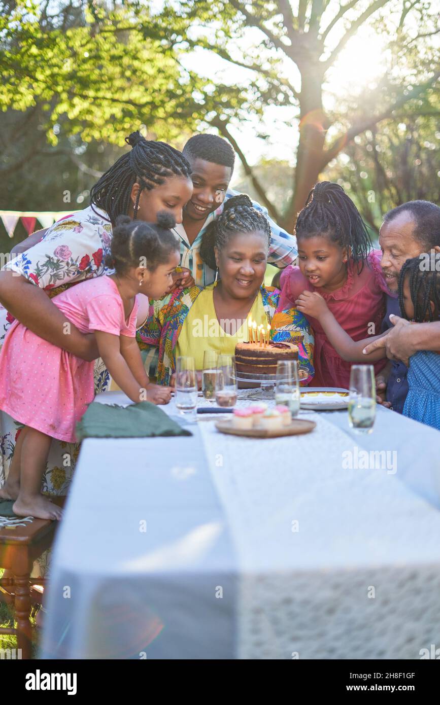 Multigenerational family celebrating birthday with cake at patio table ...
