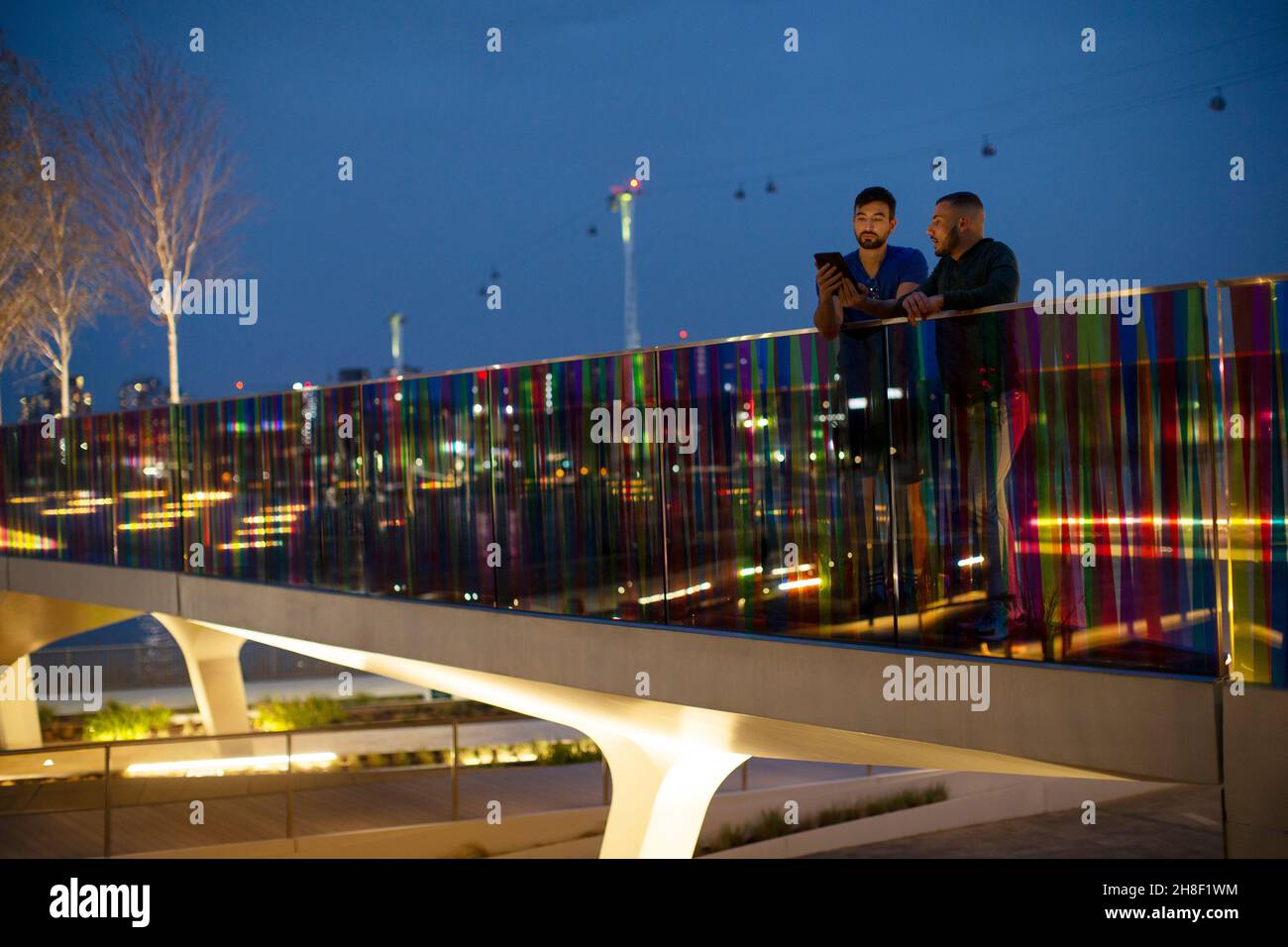 Men talking on illuminated urban footbridge at night, London, UK Stock ...