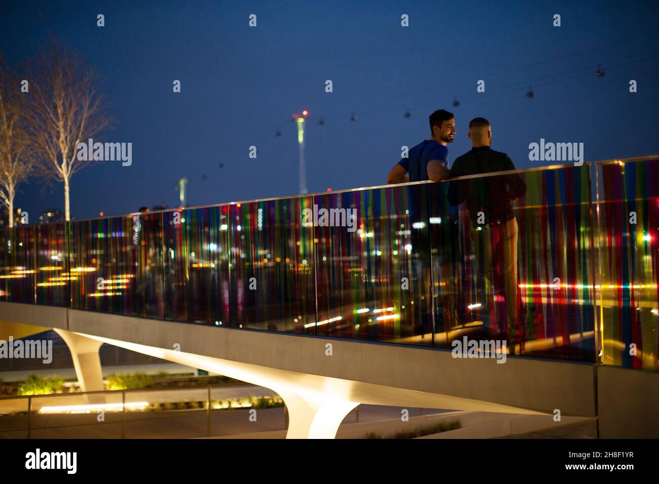 Men talking on illuminated urban footbridge at night, London, UK Stock ...