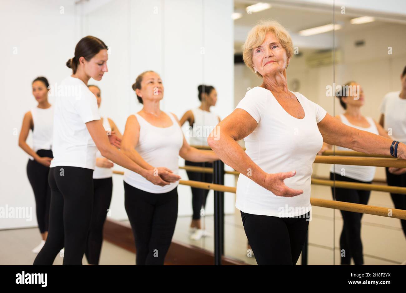 Dancing women stand in a ballet stance, where the choreographer helps ...