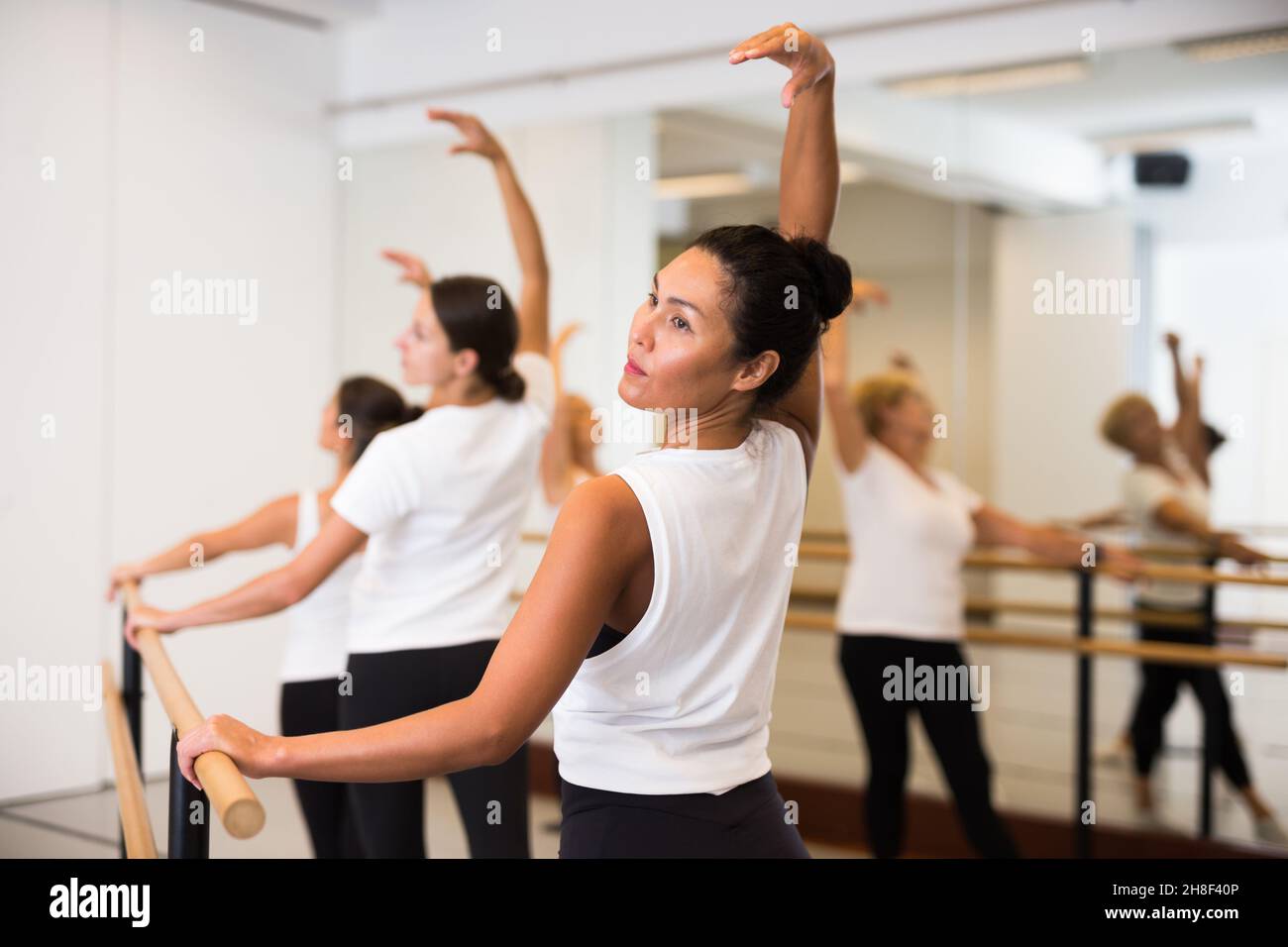 Group of women engaged in ballet in a dance studio performs a ...