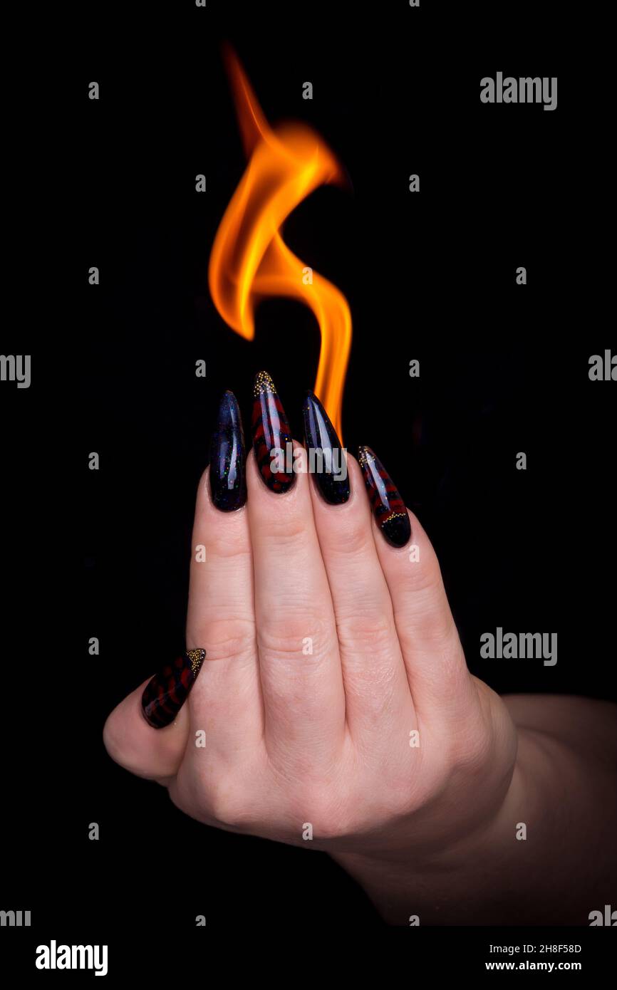 Vertical shot of a hand with long dark acrylic nails on fire isolated ...