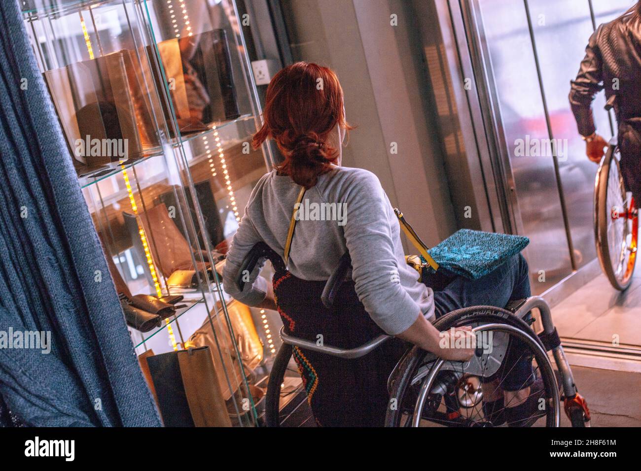 A woman in a wheelchair drives into an elevator in a shopping mall Stock Photo - Alamy