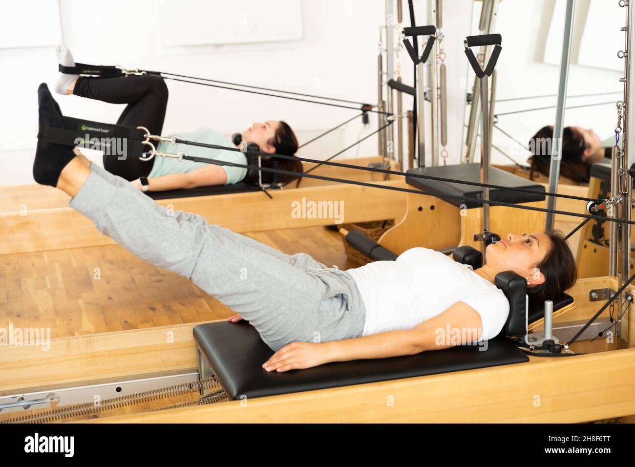 Sportswoman stretching body on pilates chair while doing forward bends ...