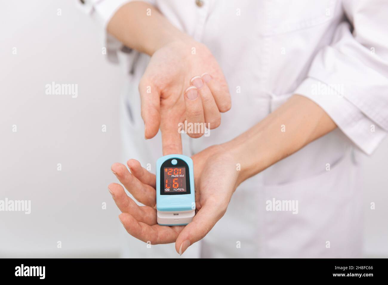 Pulse oximeter with hand of doctor isolated on white. The concept of ...