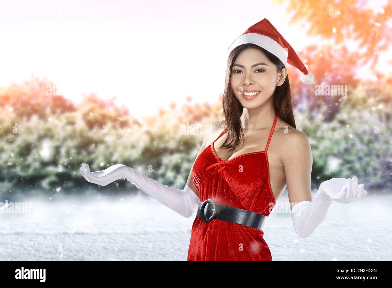 Asian woman in Santa costume standing on the snowfield with snowfall ...