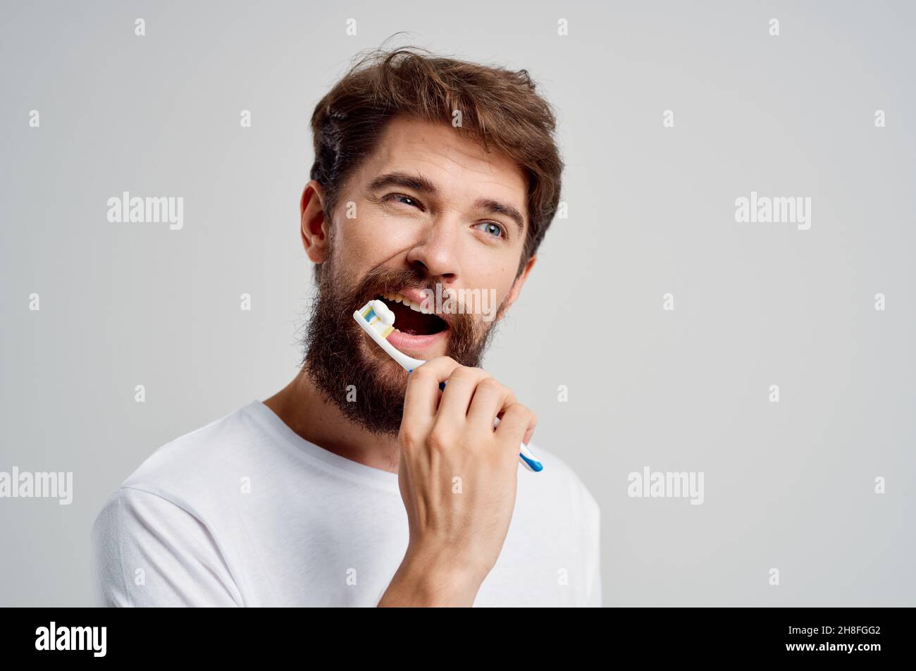 emotional man toothbrush in hand hygiene clean teeth light background ...