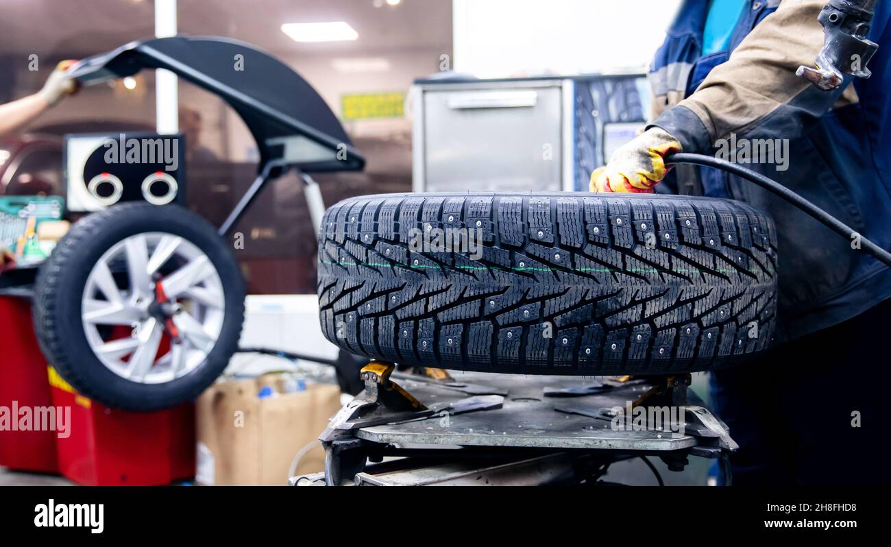 Concept car service balancing wheel. Auto mechanic places weights on ...