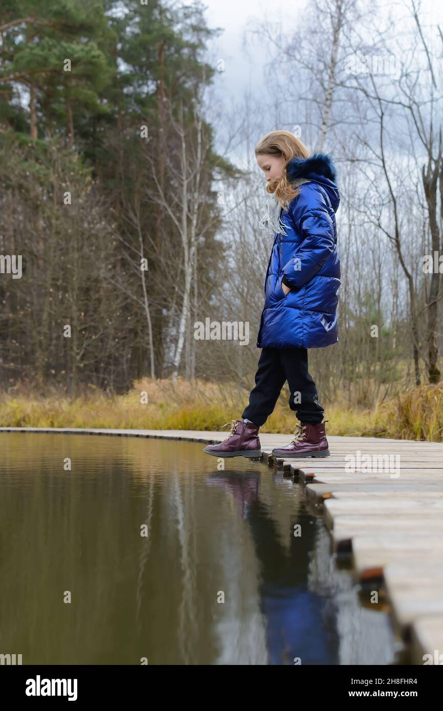 Side view of dreaming girl standing alone on edge of footbridge and ...