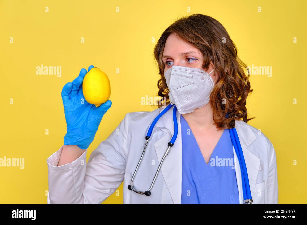 Woman doctor holding a yellow lemon on a studio background, close-up ...