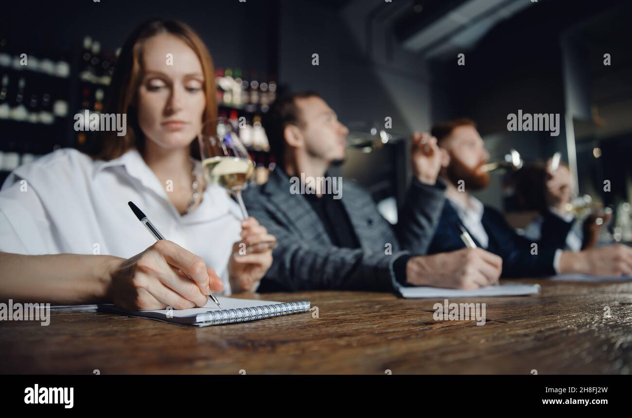 Sommeliers female and male tasting white wine and making notes at ...