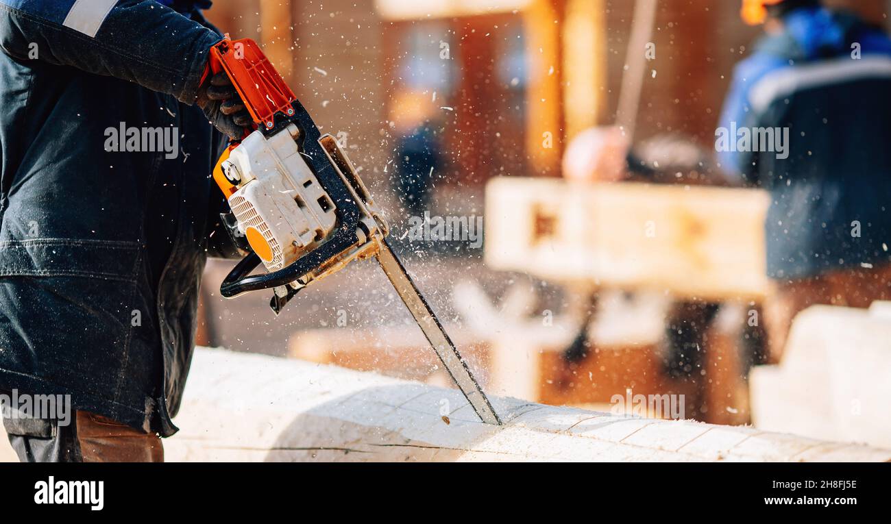 Industrial work carpenter sawing with chainsaw log, construction frame ...