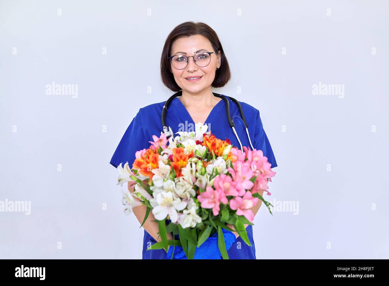 Woman doctor, nurse in blue with bouquet of flowers, on light ...
