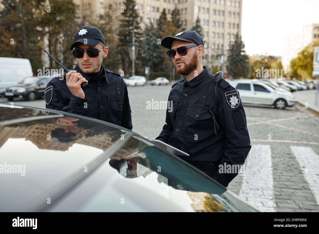 Two male police officers checking car by radio Stock Photo - Alamy