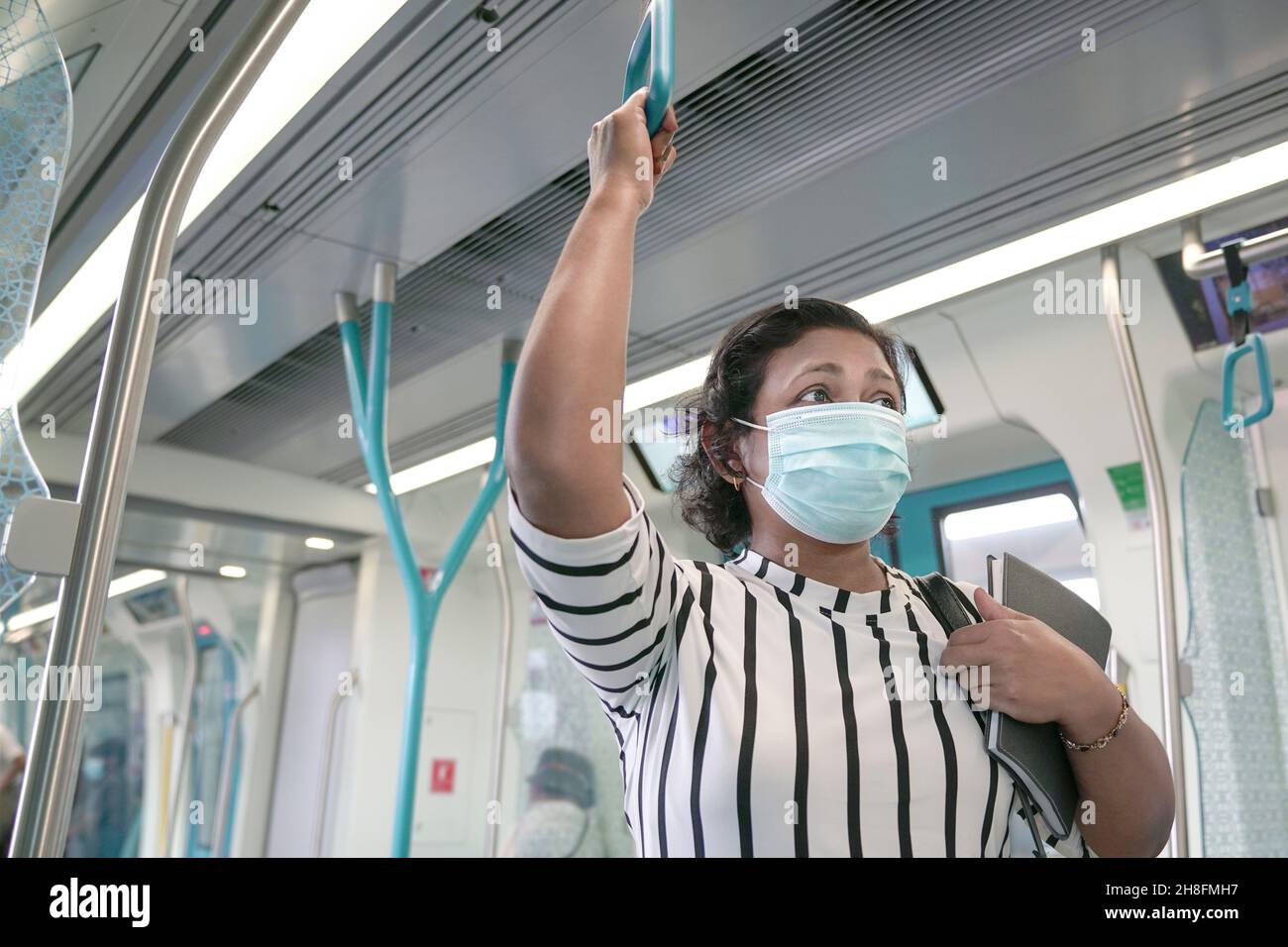 Businesswoman wearing medical face mask holding on handrails in a ...