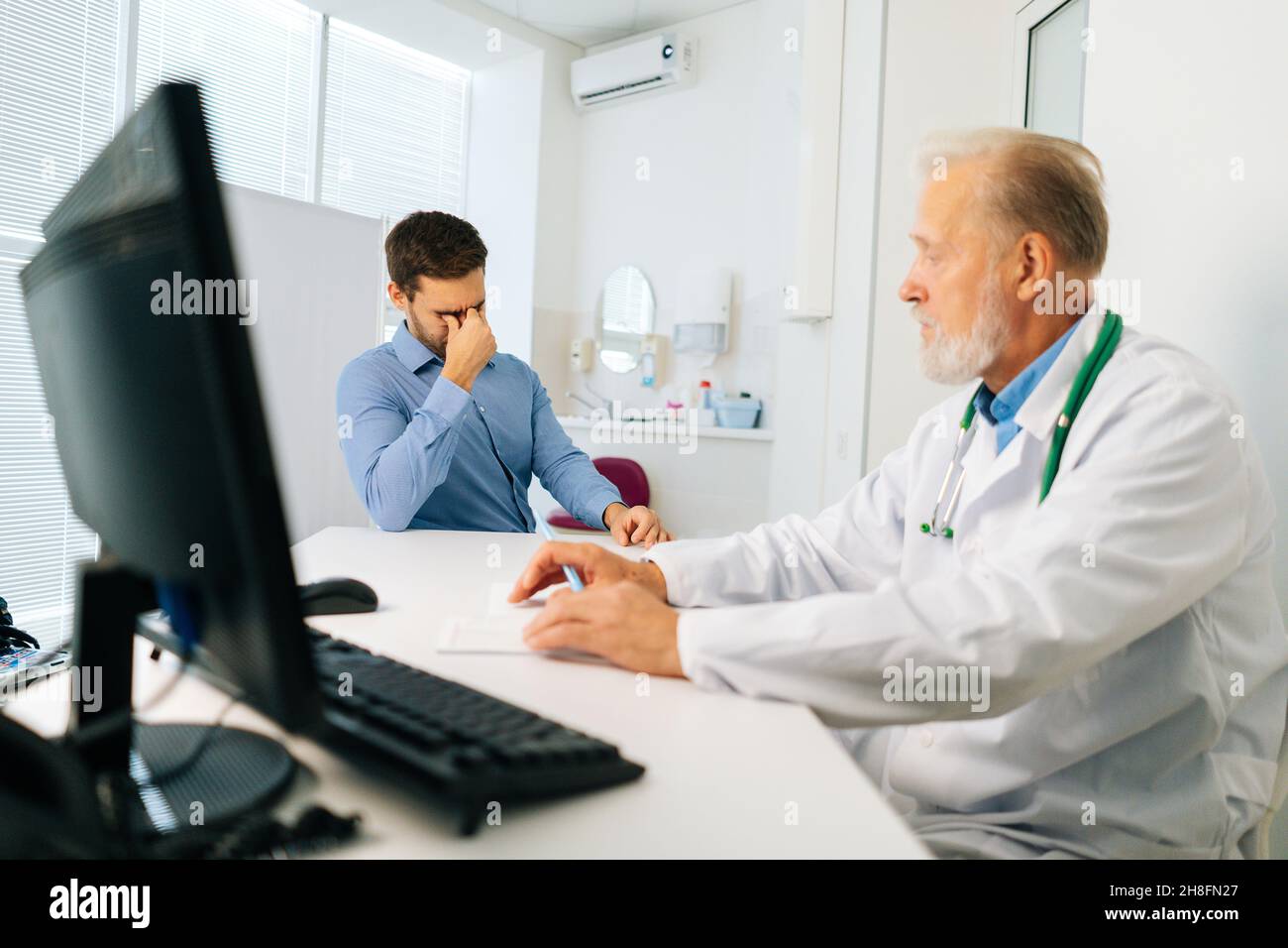 Mature adult male doctor explaining problem to crying sad young man ...