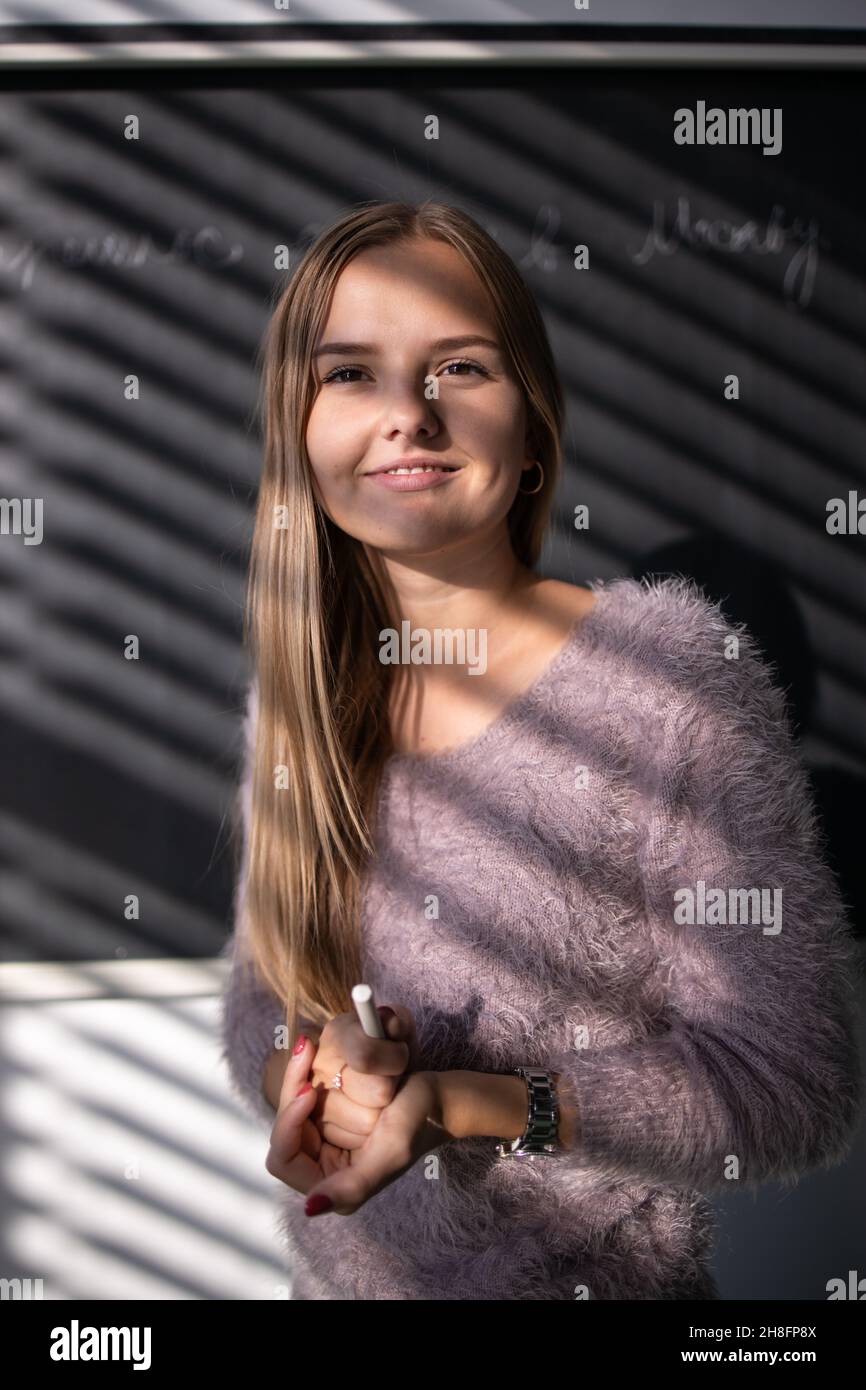 Pretty, young female student/teacher in front of a blackboard during ...