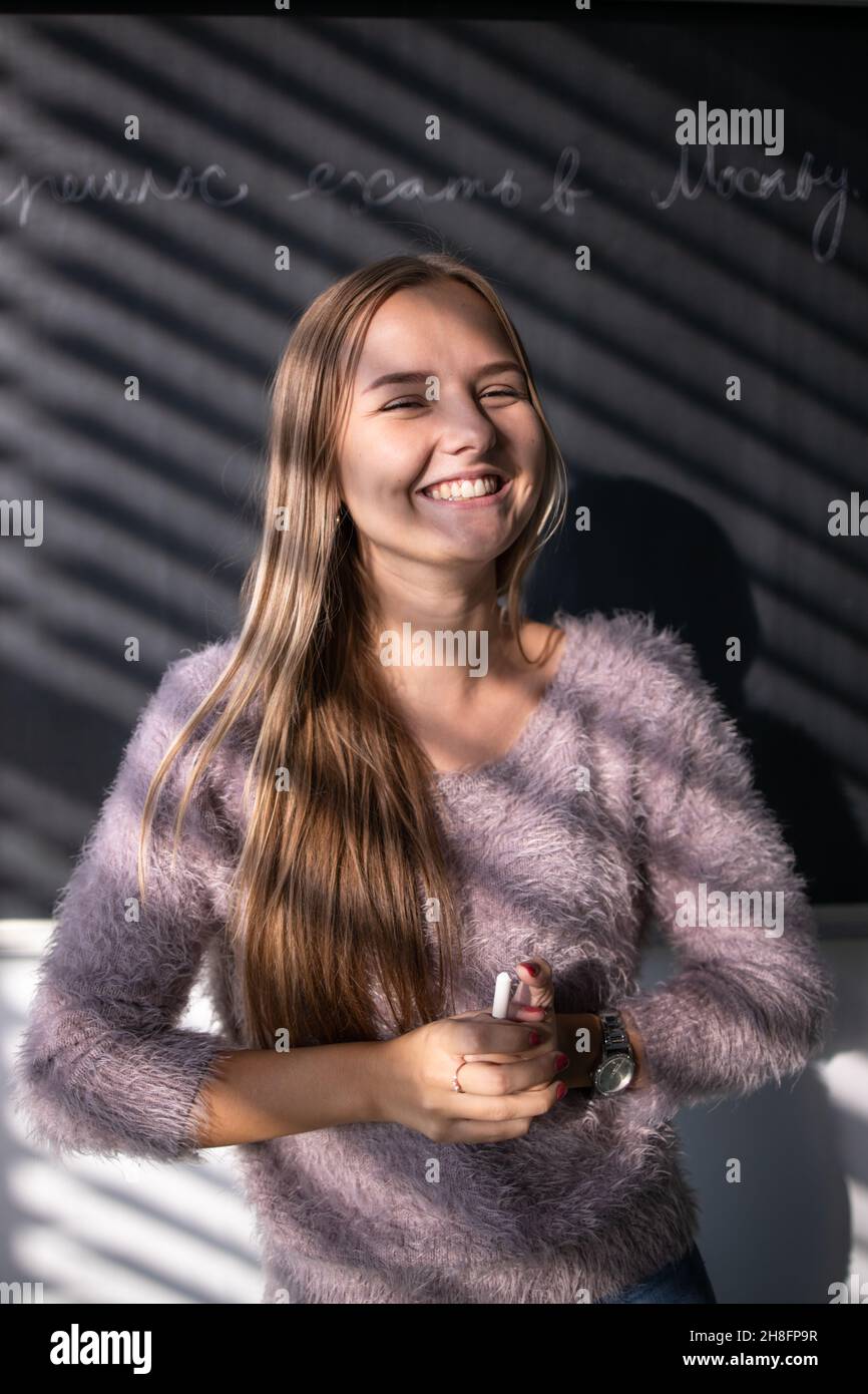 Pretty, young female student/teacher in front of a blackboard during ...
