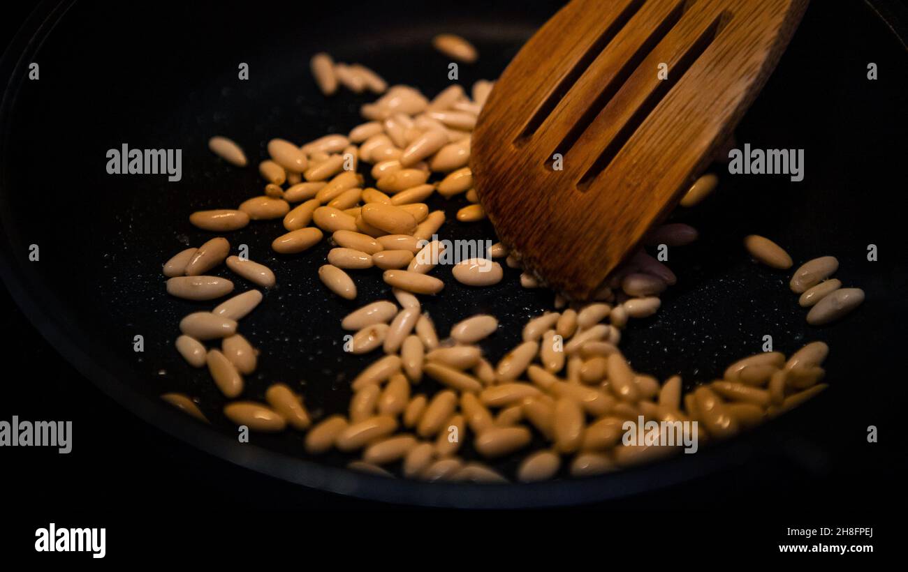 Closeup of natural fruit of pinion nut roasting on a dark skillet. Chef ...
