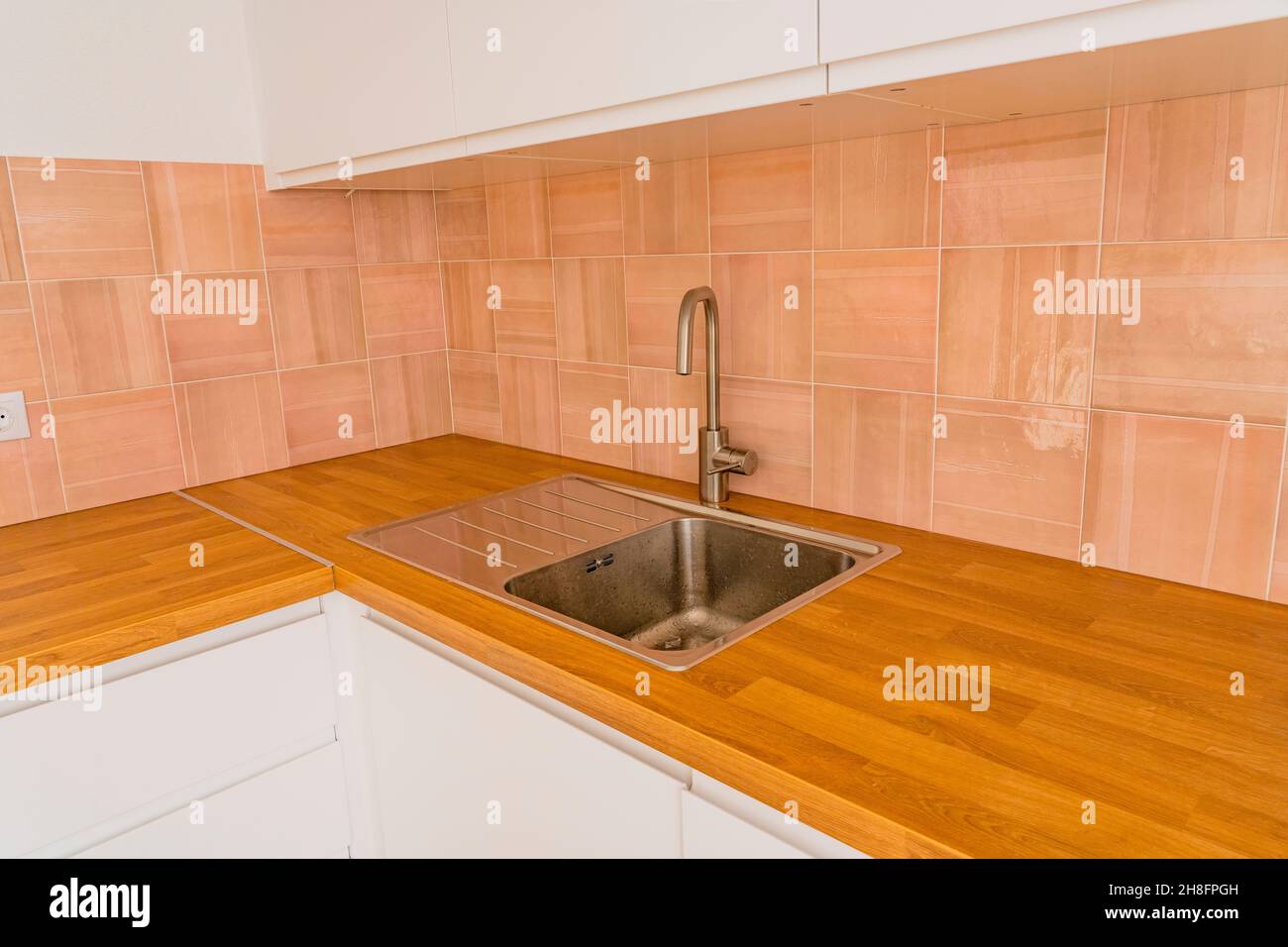 Modern kitchen interior with sink and chrome faucet, wood table top and ...