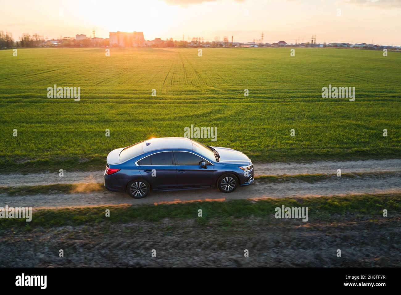 Aerial view of sedan car driving fast on dirt road at sunset. Traveling ...